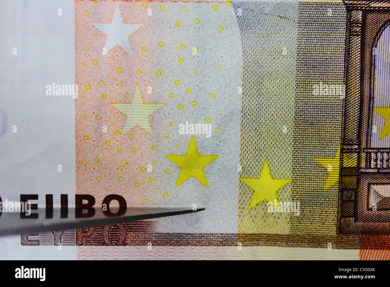 cutting a 50 Euro note - the word EURO is split and reflects the word ...
