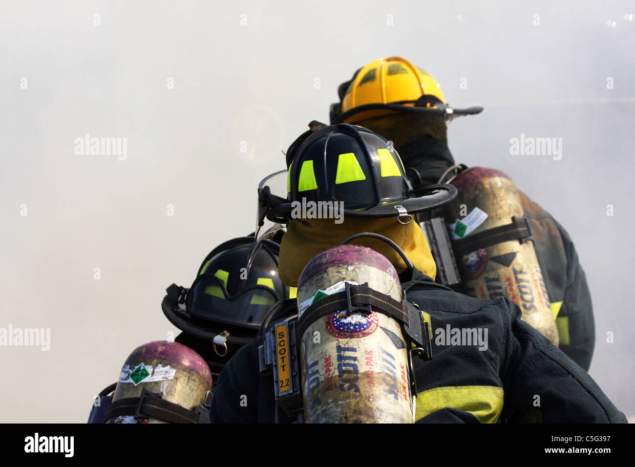 Three fire fighters surrounded by smoke fighting a fire Stock Photo - Alamy