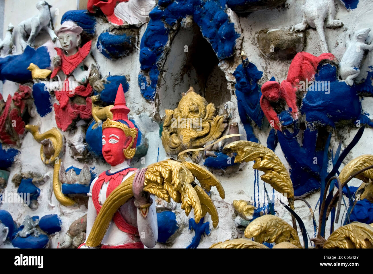 A colorful red Buddha and wall sculptures decorate a Buddhist temple in ...