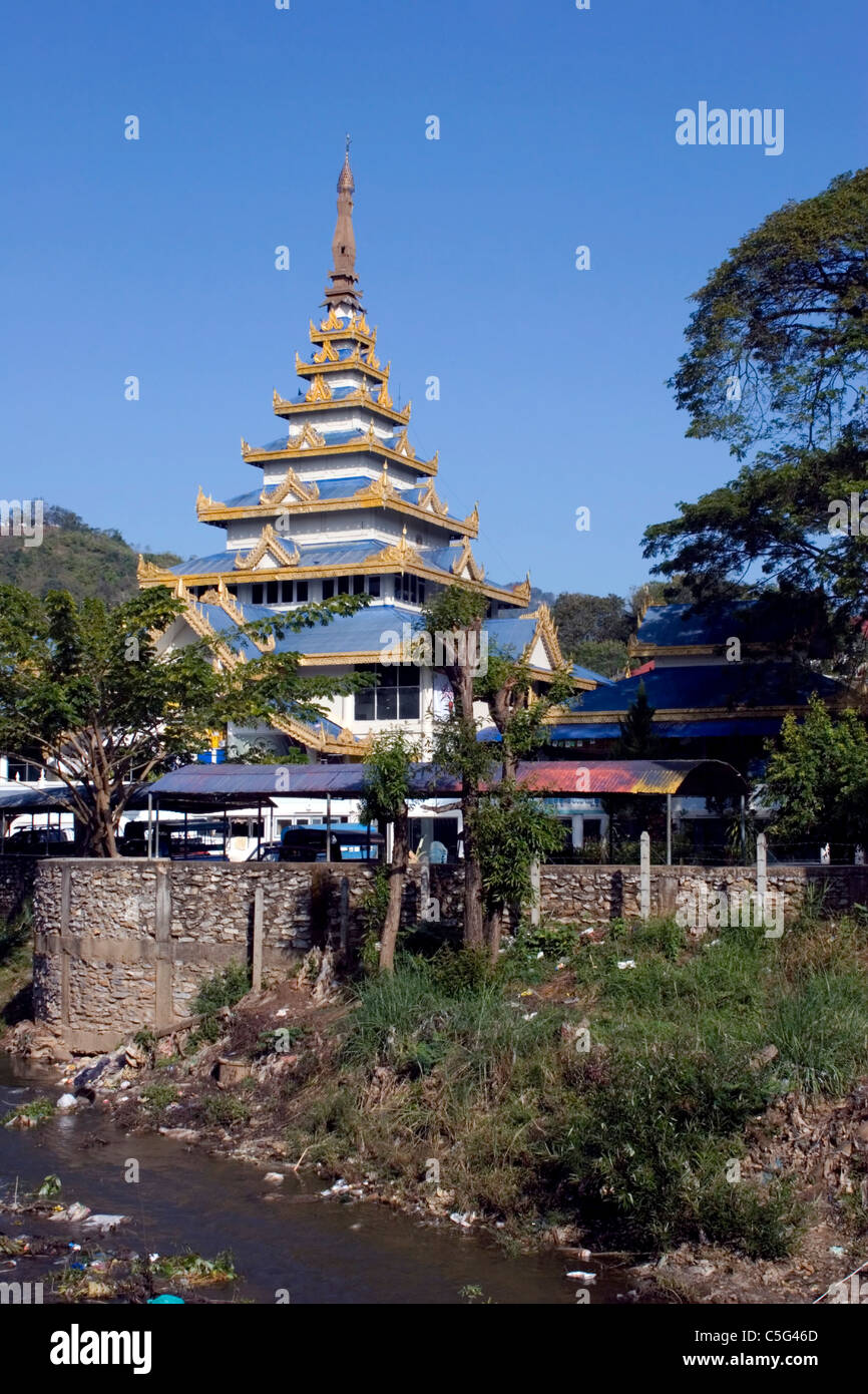 A Burmese style Buddhist temple overlooks a dirty and polluted river in ...
