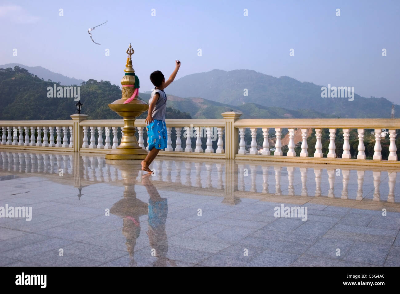 A young boy is flying a kite on an observation deck that overlooks ...