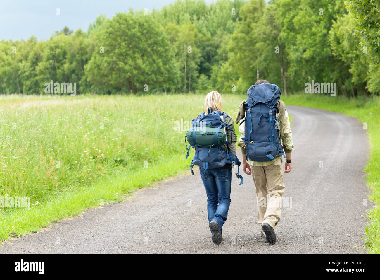 Hiking young couple backpack tramping on asphalt road countryside Stock ...