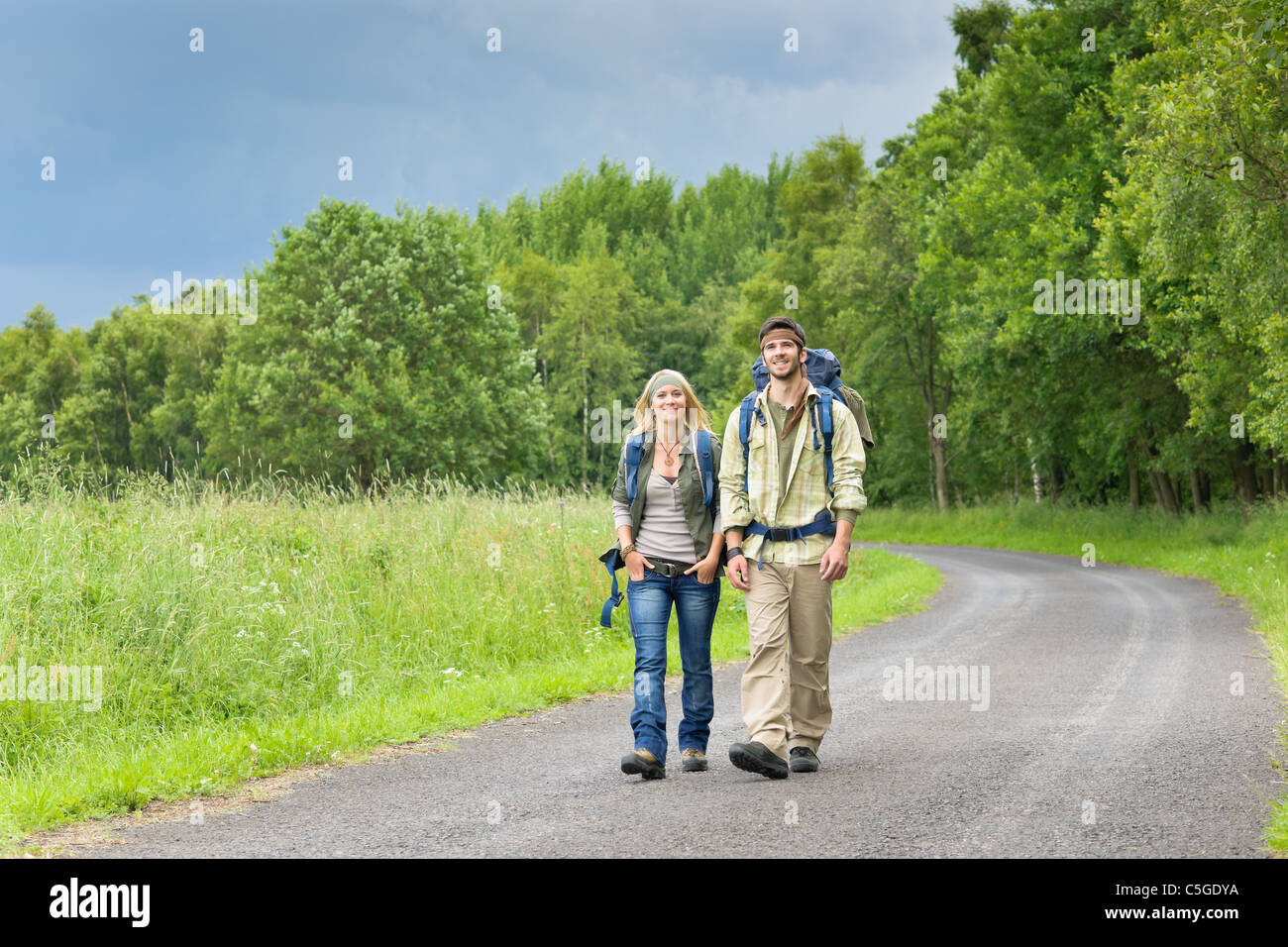 Hiking young couple backpack tramping on asphalt road countryside Stock ...