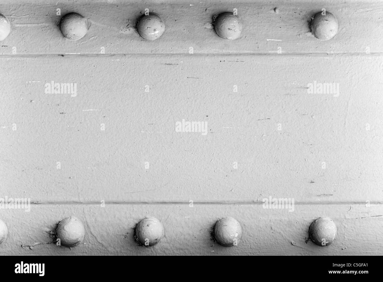 A silver painted metal background texture with four rusted bolts or ...