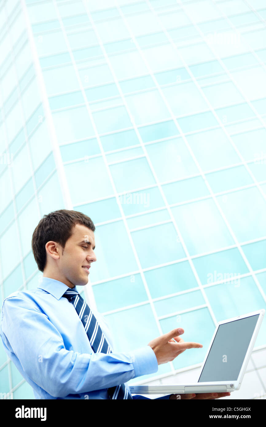 Young businessman using computer by office building Stock Photo - Alamy