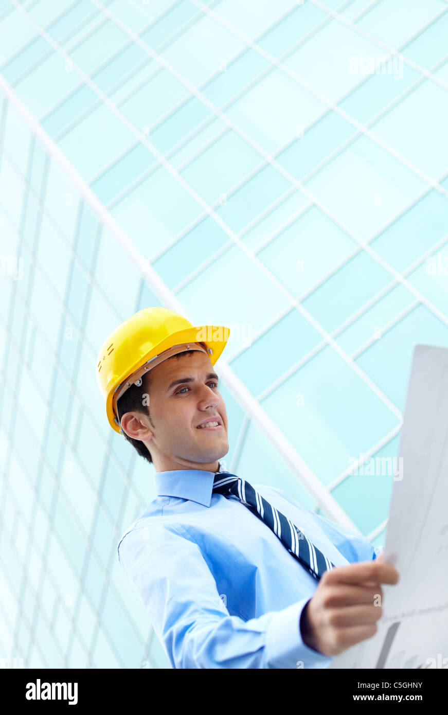 Young engineer looking at paperwork by office building Stock Photo - Alamy