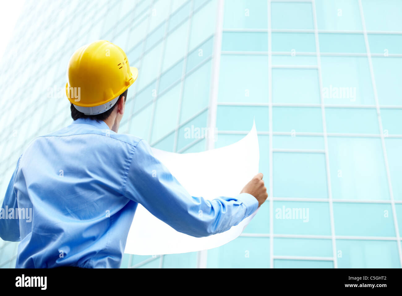 Rear view of architect looking comparing housing project with building ...