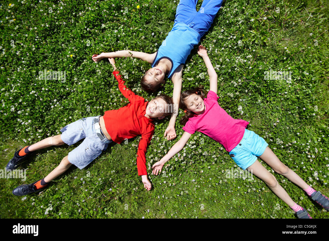 Three children having break on grass Stock Photo - Alamy