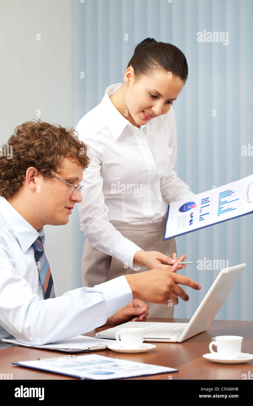 Businessman sitting at table and giving instructions to his secretary ...