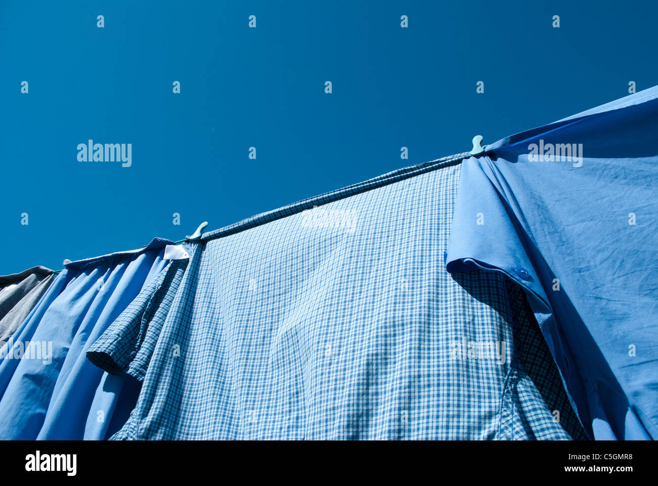 Blue washing on washing line against deep blue clear sky from below ...