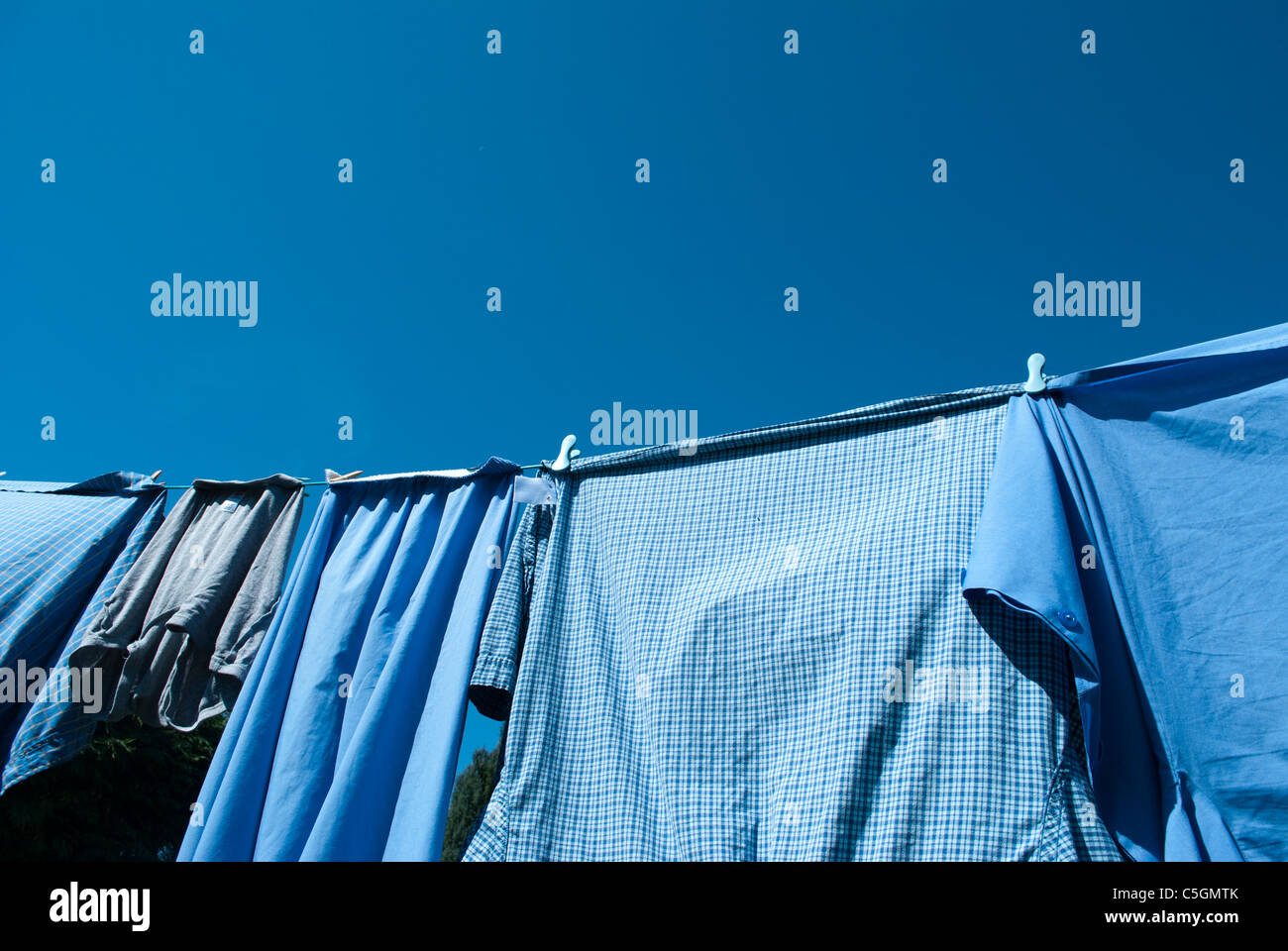 Blue washing on washing line against deep blue clear sky shot upwards ...