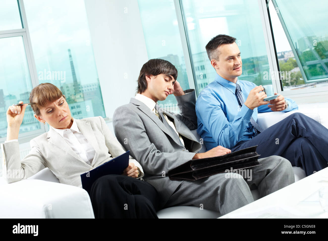 Three office workers sitting on sofa after hard workday Stock Photo - Alamy