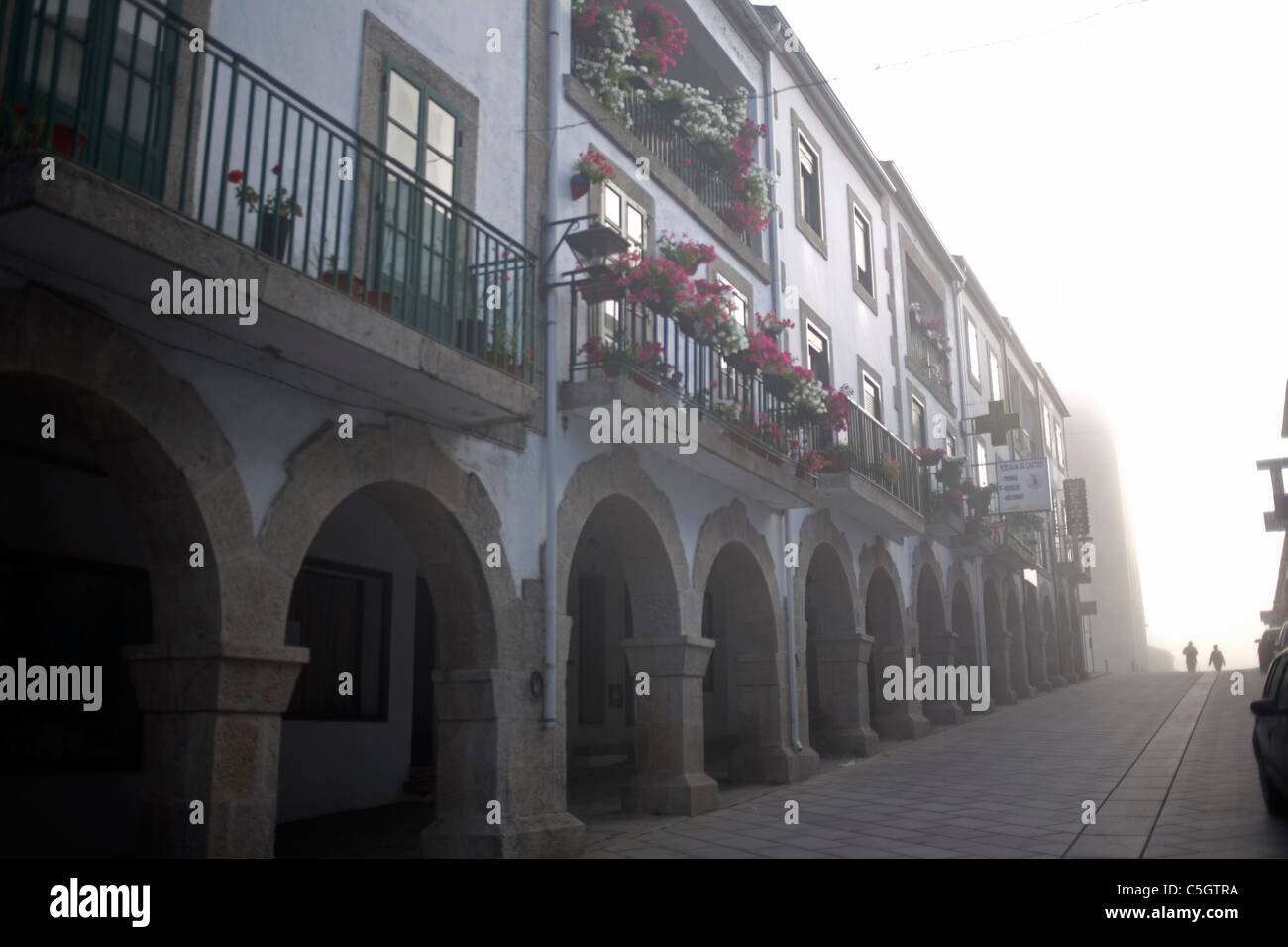 Pilgrims walk through the early morning fog in Portomarin town, Galicia ...