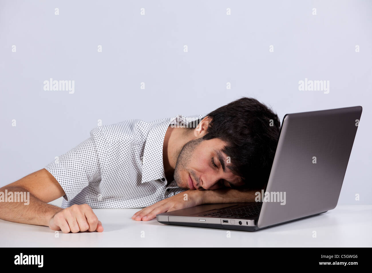 young man sleeping next to his laptop computer (with gray background ...
