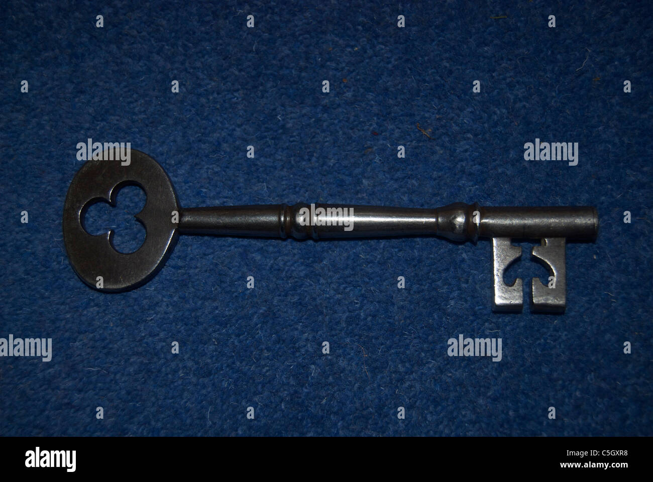 An old, large, church door key, pictured on a blue felt background ...