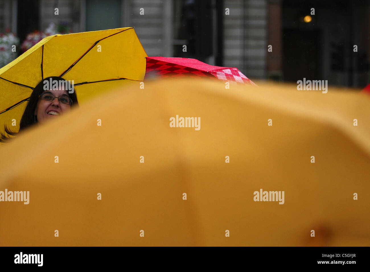 A face looking up (at Nelsons column) from a group of open umbrellas ...