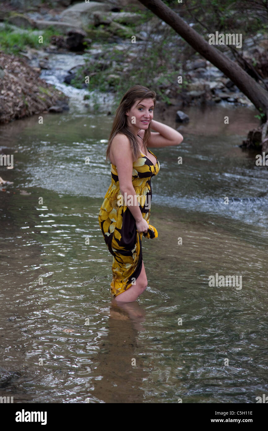 Pretty woman in yellow dress wading in a shallow creek Stock Photo - Alamy