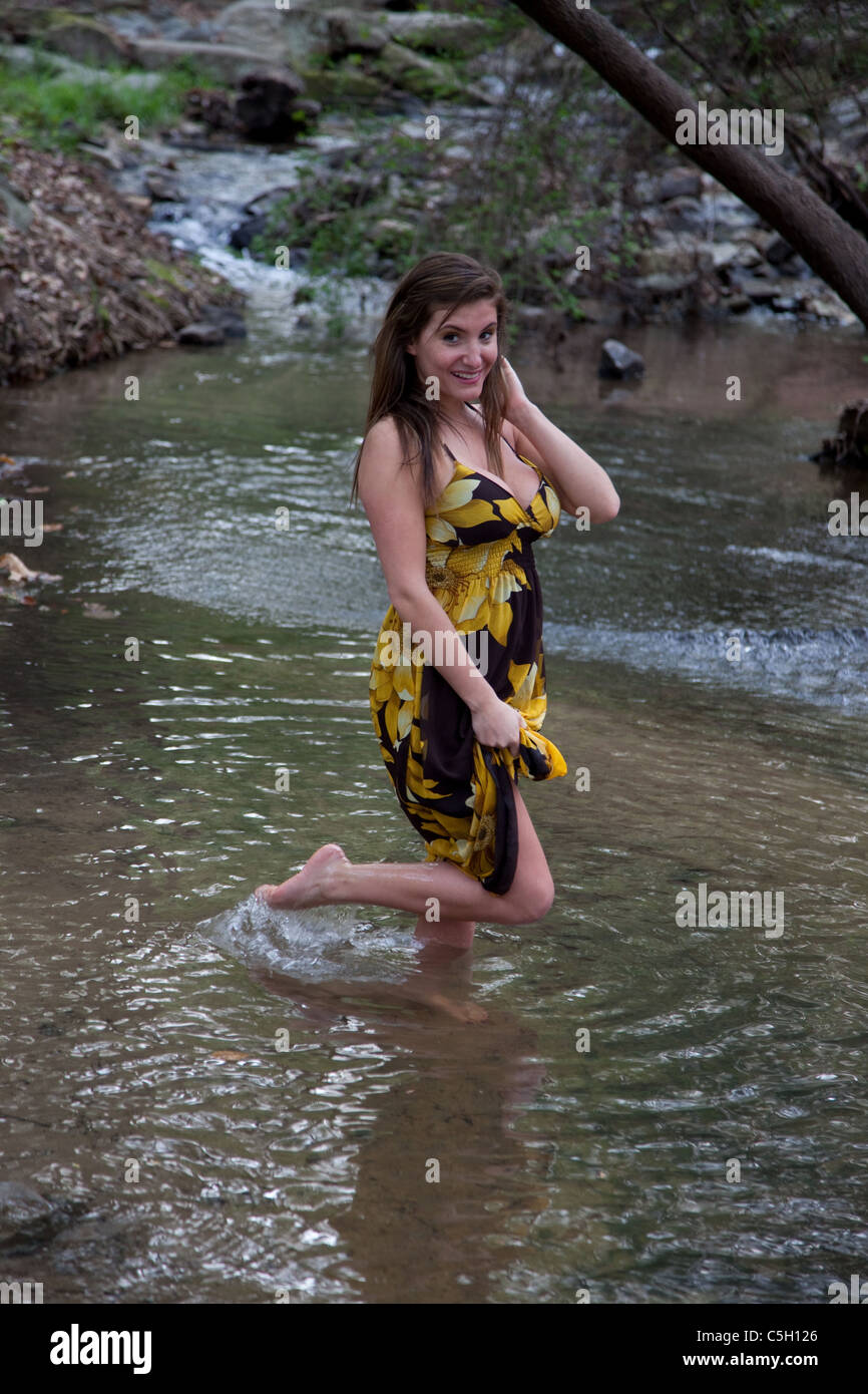 Pretty woman in yellow dress wading in a shallow creek Stock Photo - Alamy
