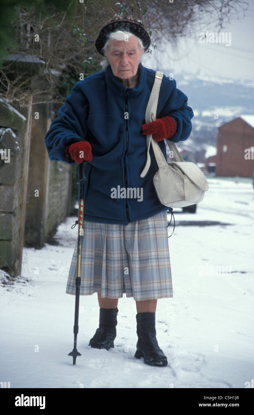 old lady with walking stick walking uphill in snow Stock Photo - Alamy