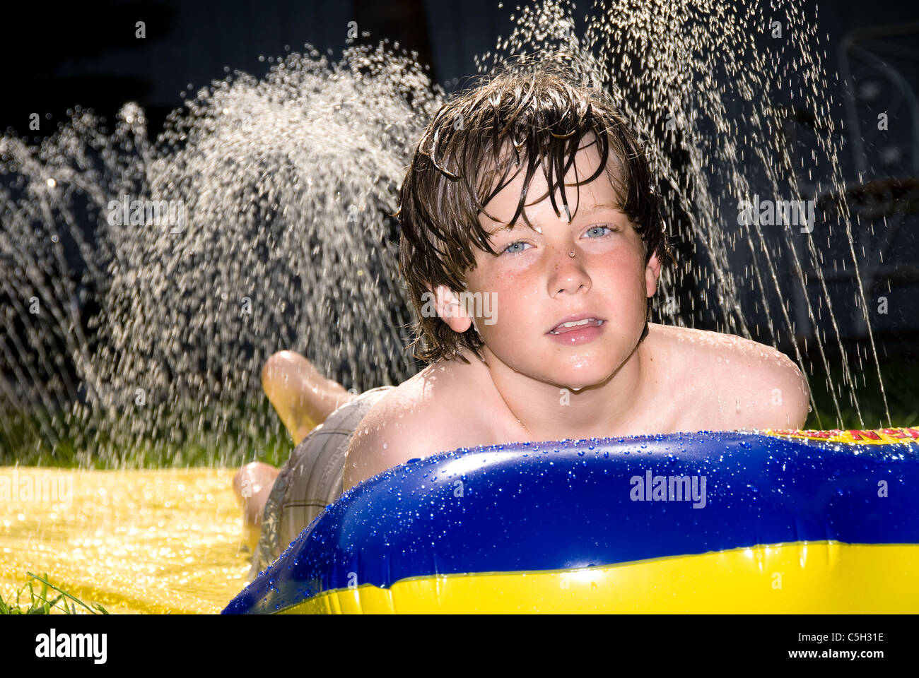 A kid slides down a slippery water slider during a hot summer day Stock ...