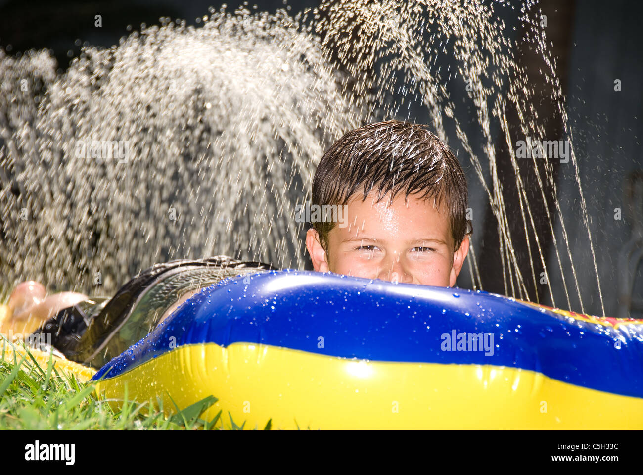 A kid slides down a slippery water slider during a hot summer day Stock ...