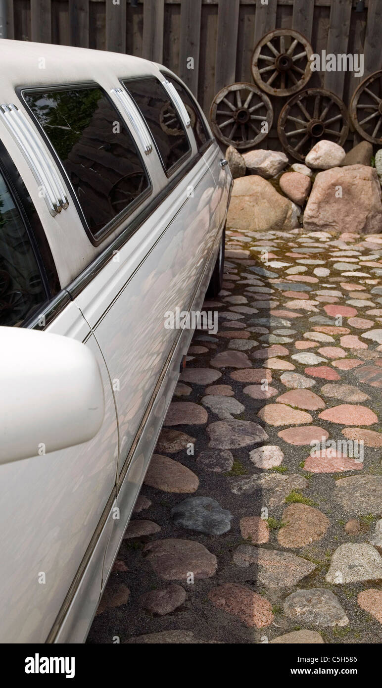 There is a white limousine with black windows on way made from stone ...