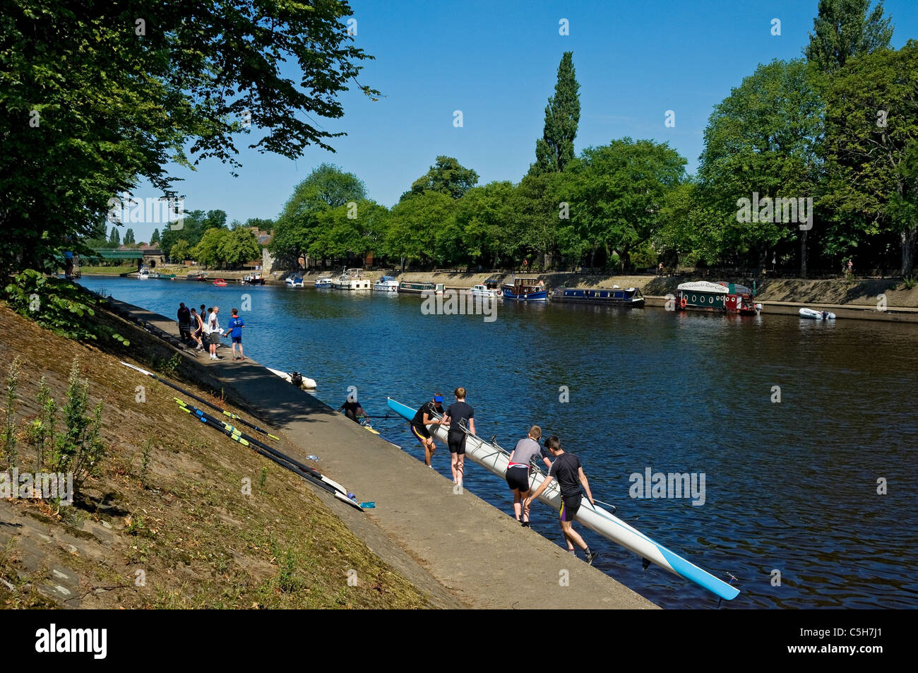 Rowing rowers crew putting boat onto River Ouse in summer York North ...