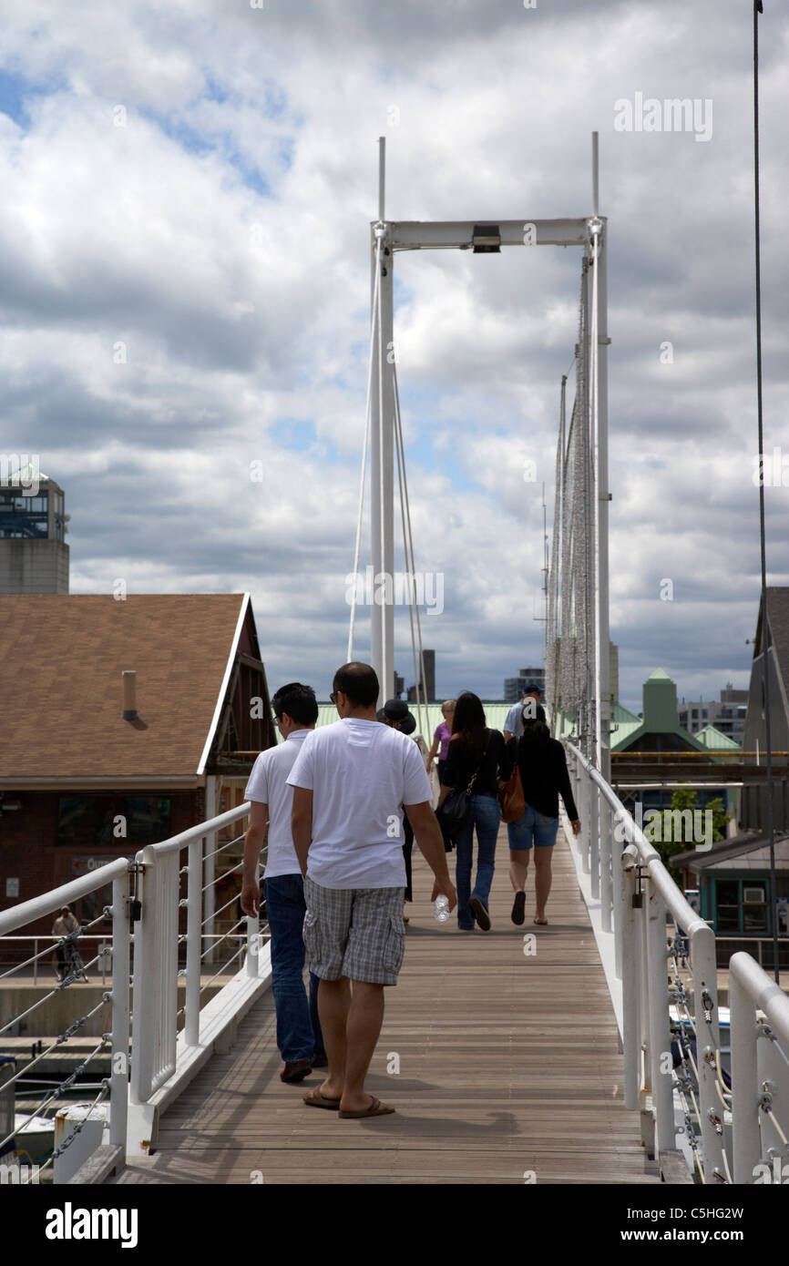 people walking over pedestrian bridge in harbourfront marina toronto ...