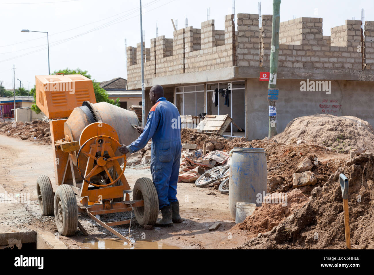 Construction worker operating cement mixer on road building site, Accra ...