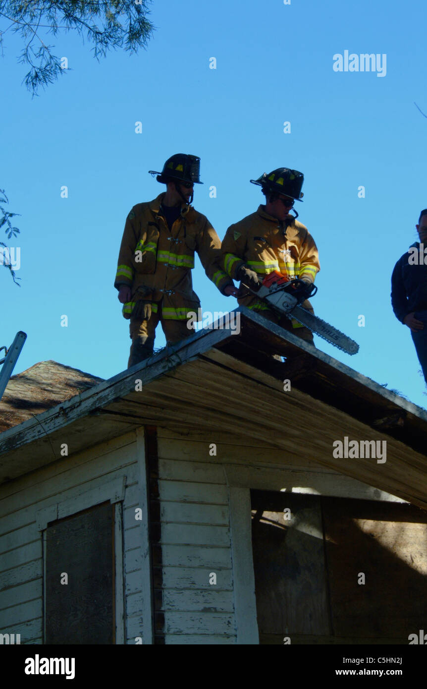 Two firefighters are silhouetted as they are about to cut a ventilation ...