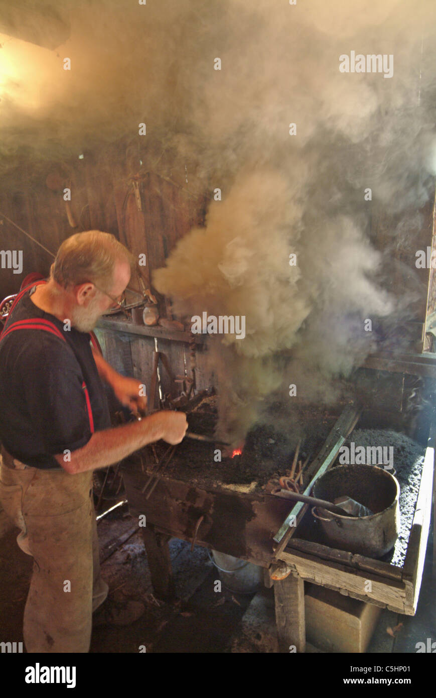 A blacksmith pumps more air into the coal fed fire to make it burn ...