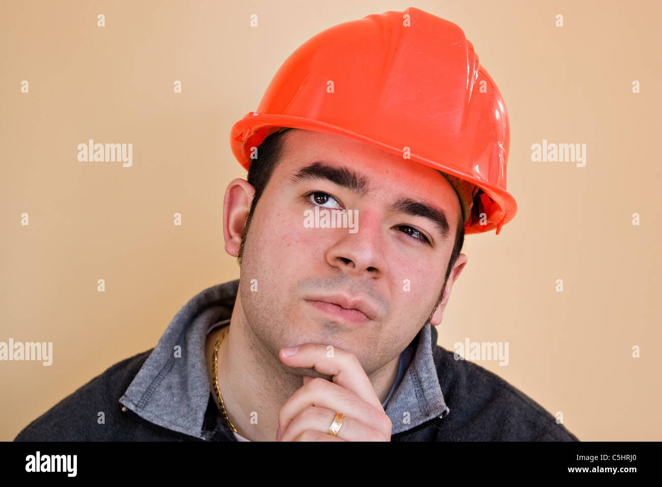 A young construction working with a pensive or contemplative look ...