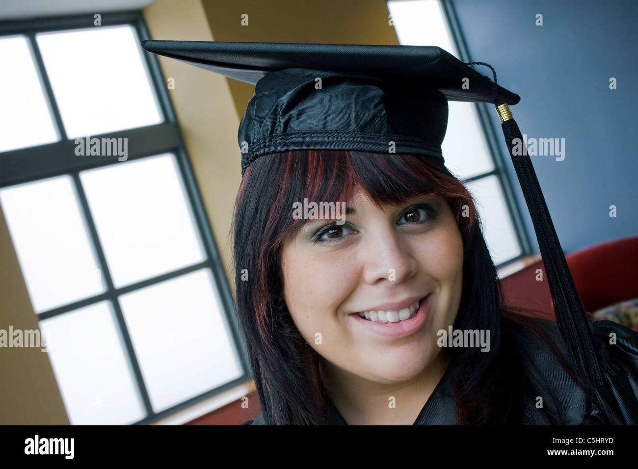 A recent school graduate posing in her cap and gown indoors Stock Photo ...