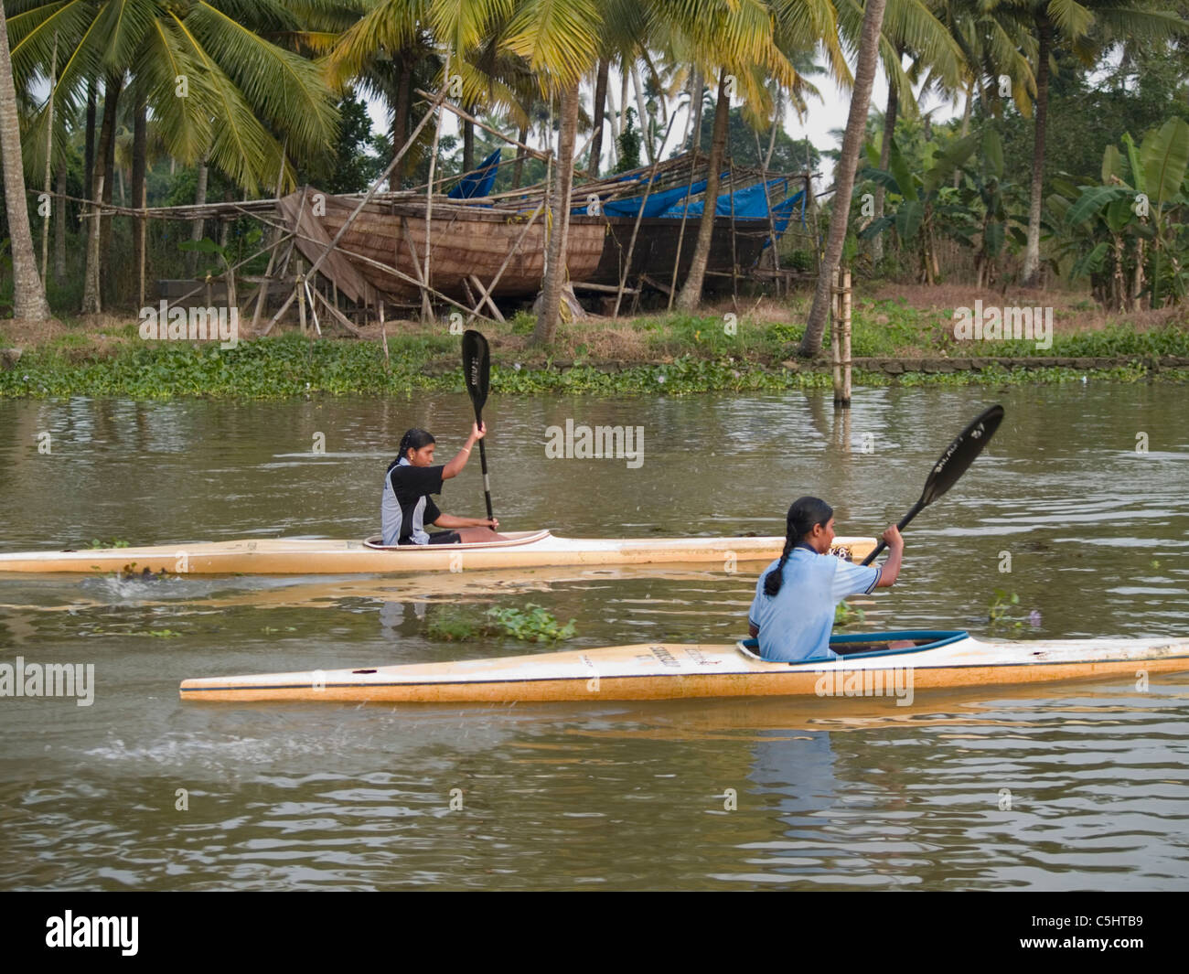 Competitive rowers practice rowing as they pass traditional local boats ...