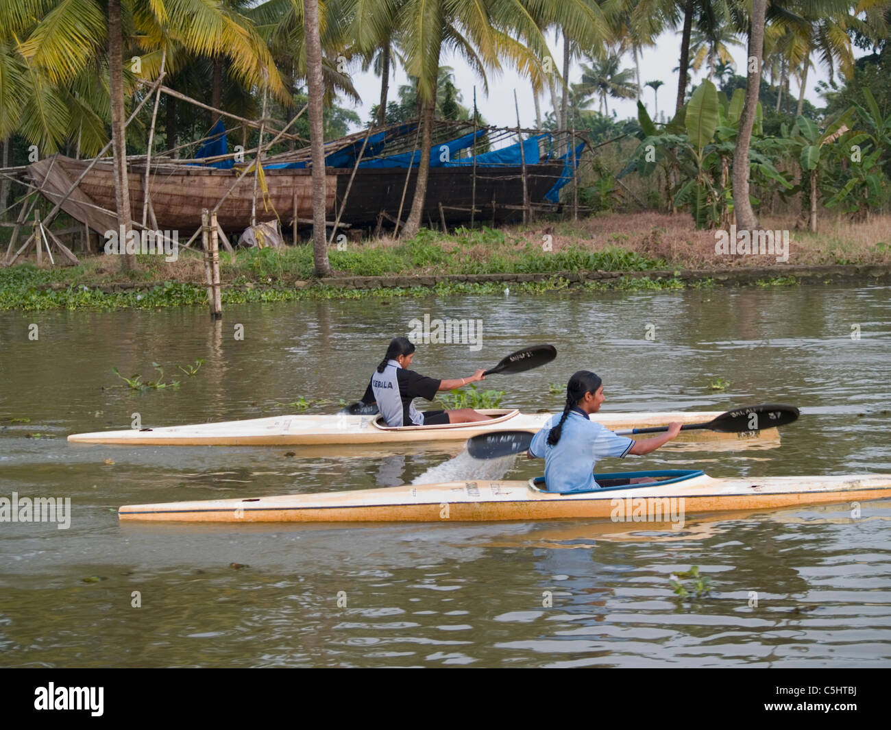 Competitive rowers practice rowing as they pass traditional local boats ...