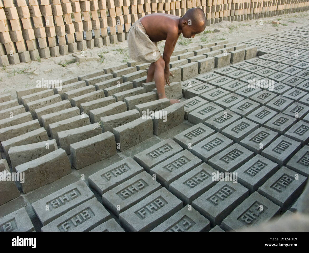 Laborers, including a child, turn drying bricks in Dacca, Bangaldesh ...
