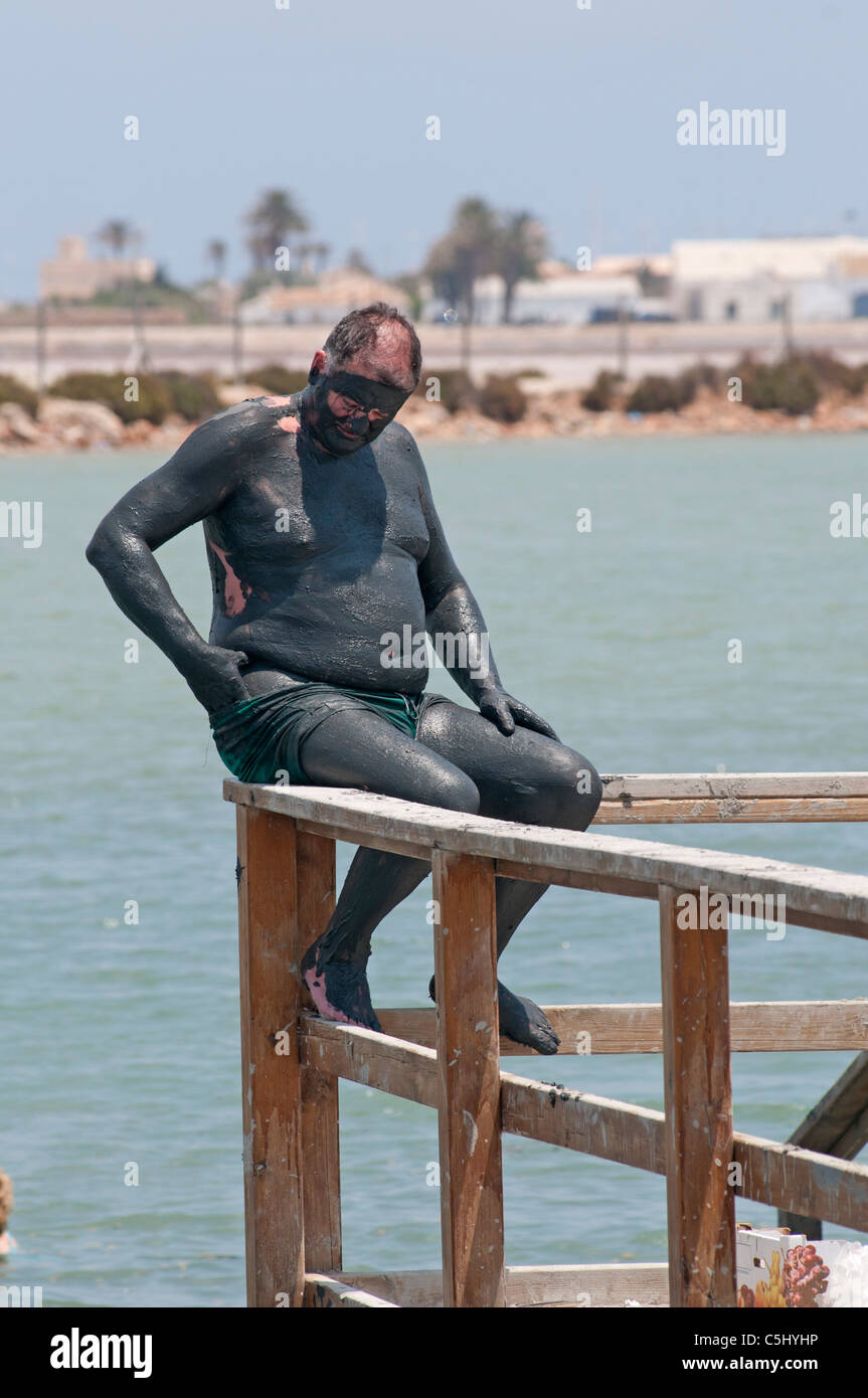Man cover's himself in therapeutic mud from Lo Pagan beach, Lo Pagan ...