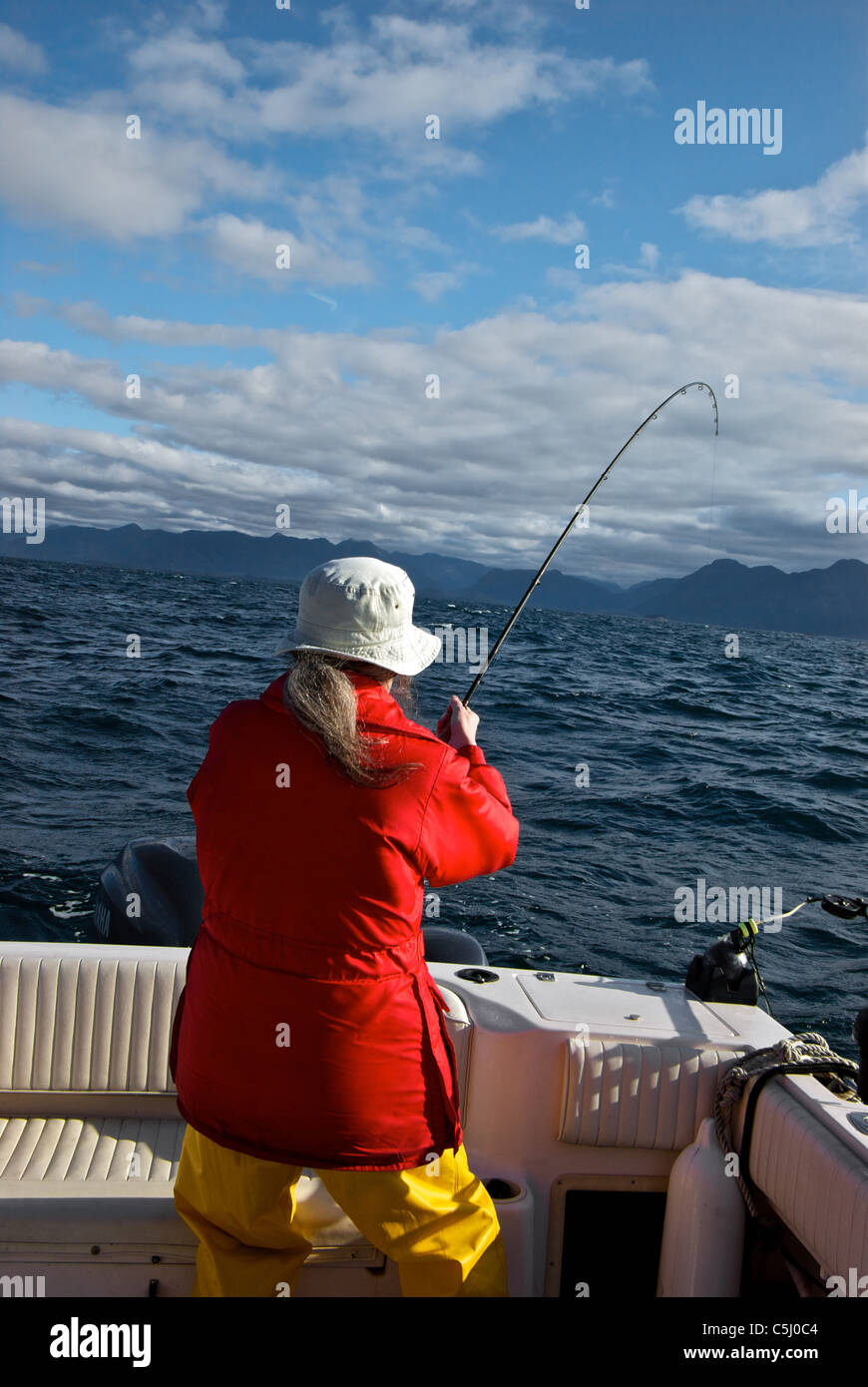 Female sport fishing angler playing Chinook salmon rough seas open ...