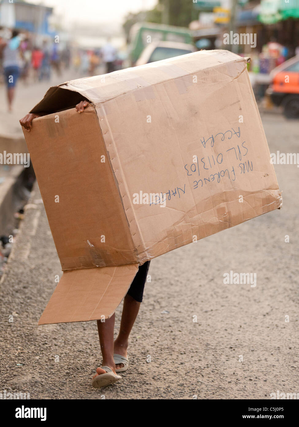 African boy covered by cardboard box, walking in street, Osu Market ...