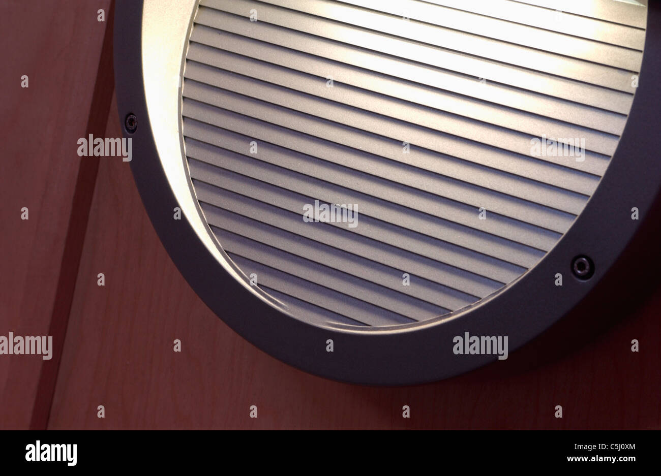 round porthole window with slatted grille set in a brown wood wall ...