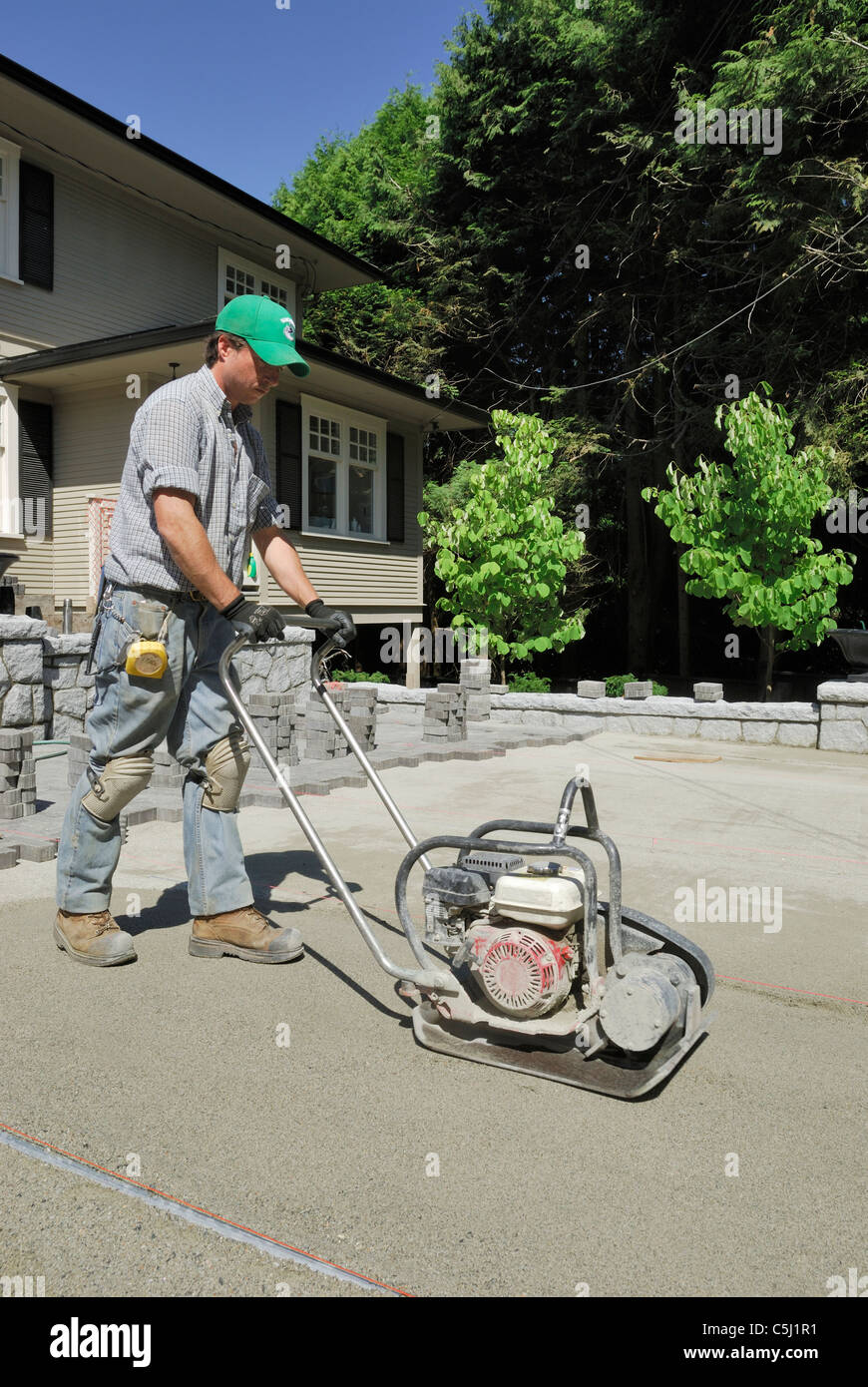 Worker compacting sand making it ready for paver installation Stock ...