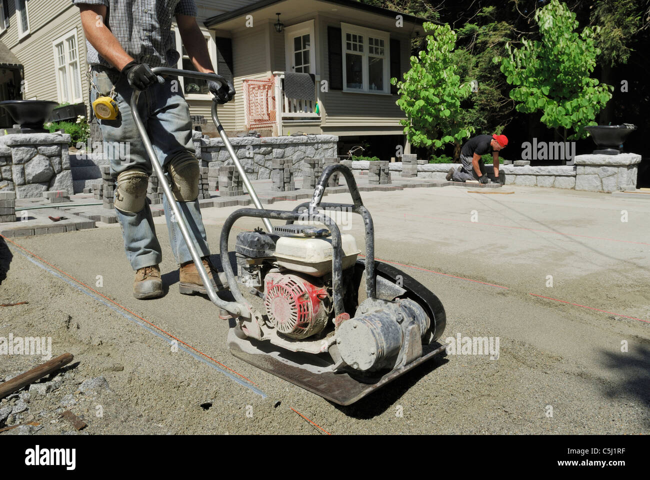 Worker compacting sand making it ready for paver installation Stock ...