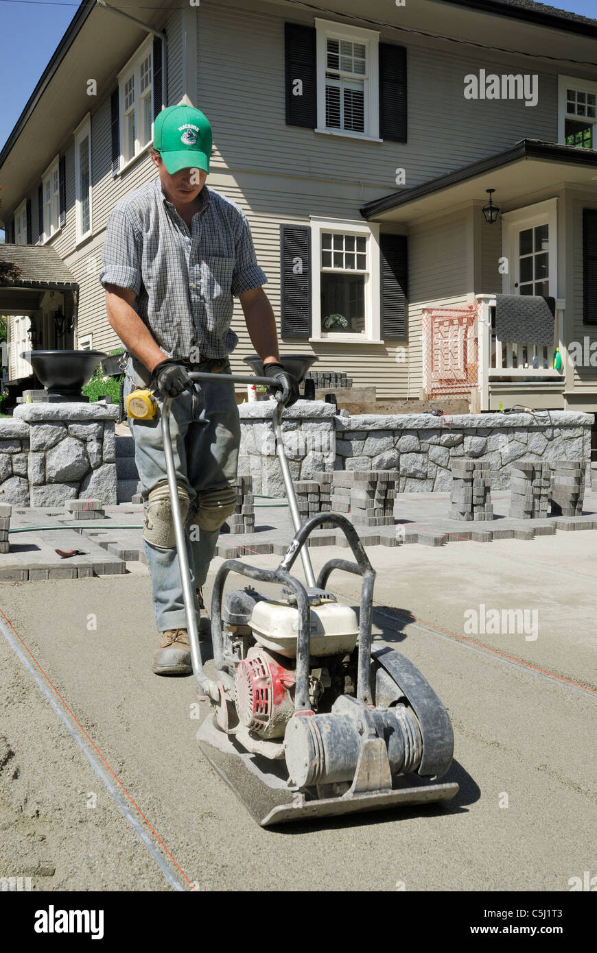 Worker compacting sand making ready for paver installation Stock Photo ...