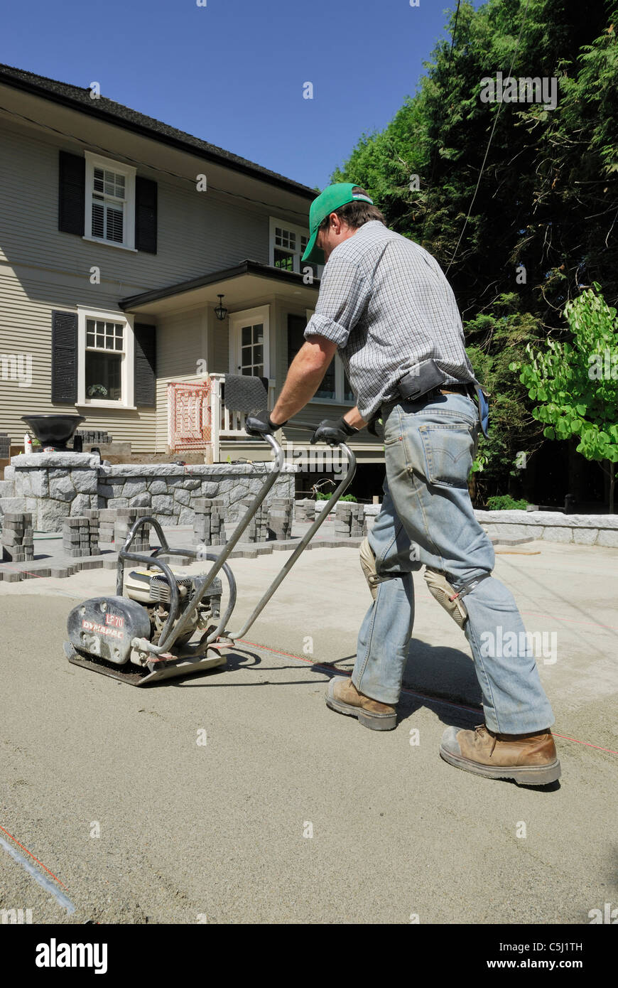 Worker compacting sand making it ready for paver installation Stock ...