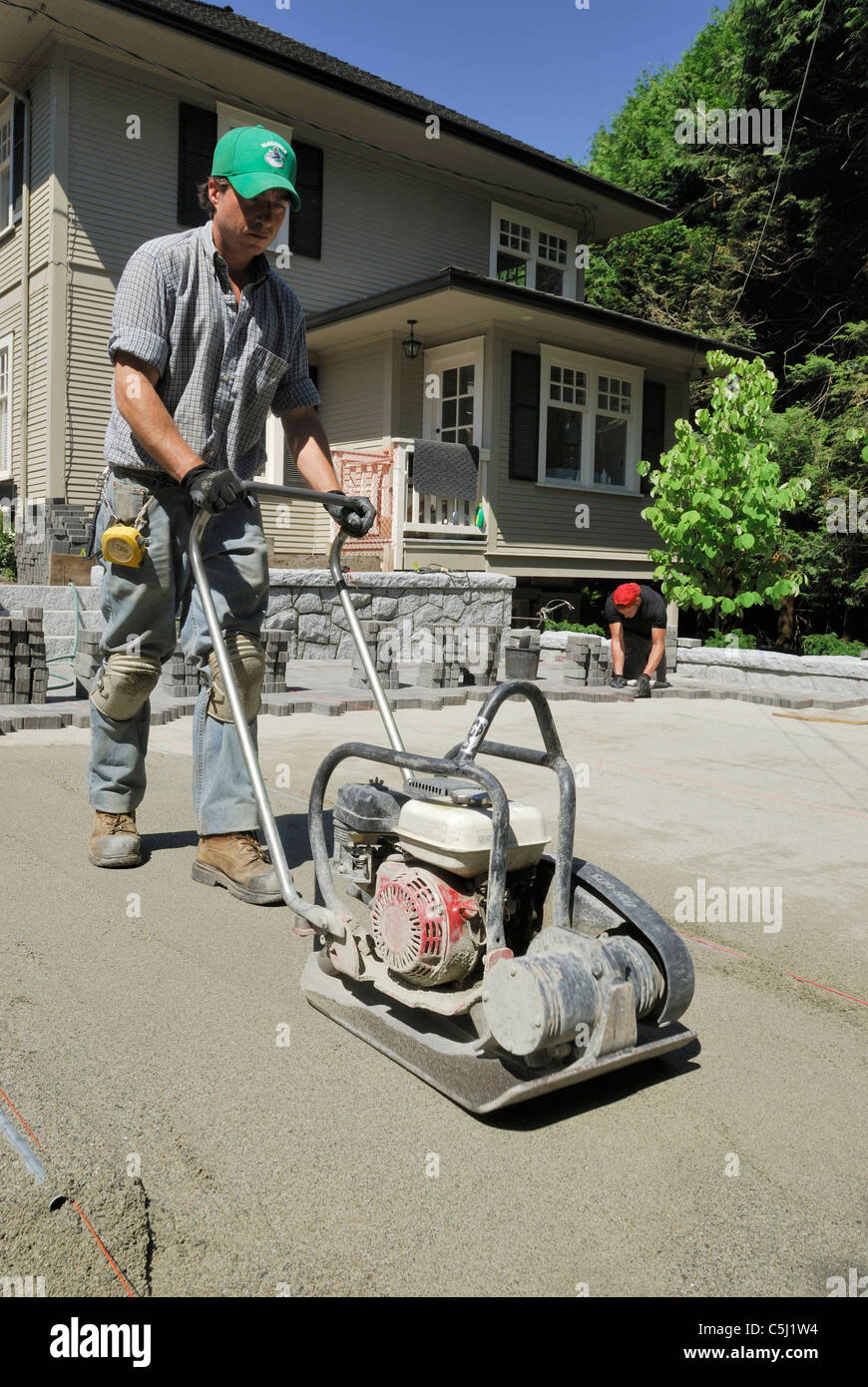 Worker compacting sand making it ready for paver installation Stock ...