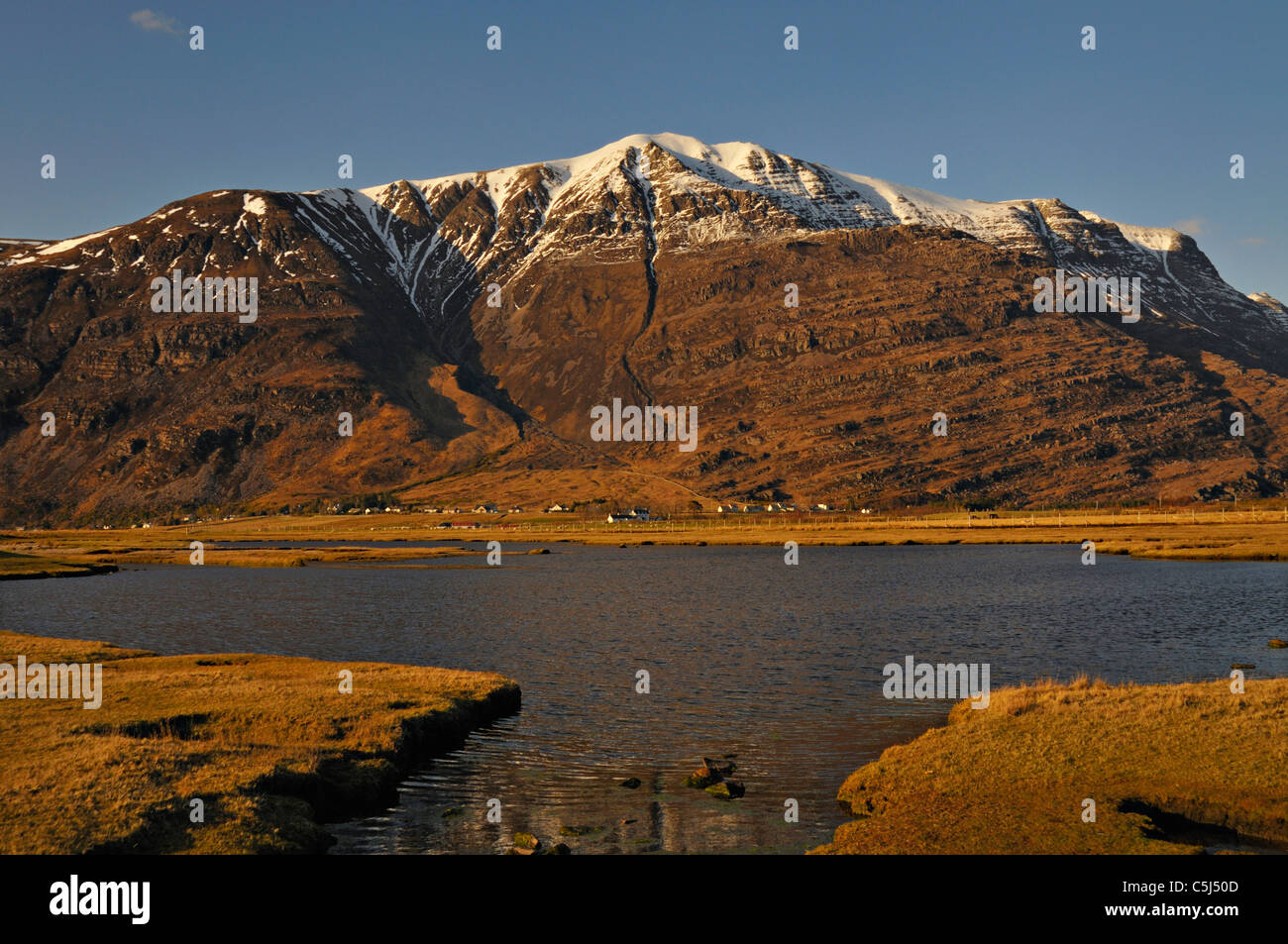 The distant snow-capped peak of Liathach rises above a nearby tidal ...