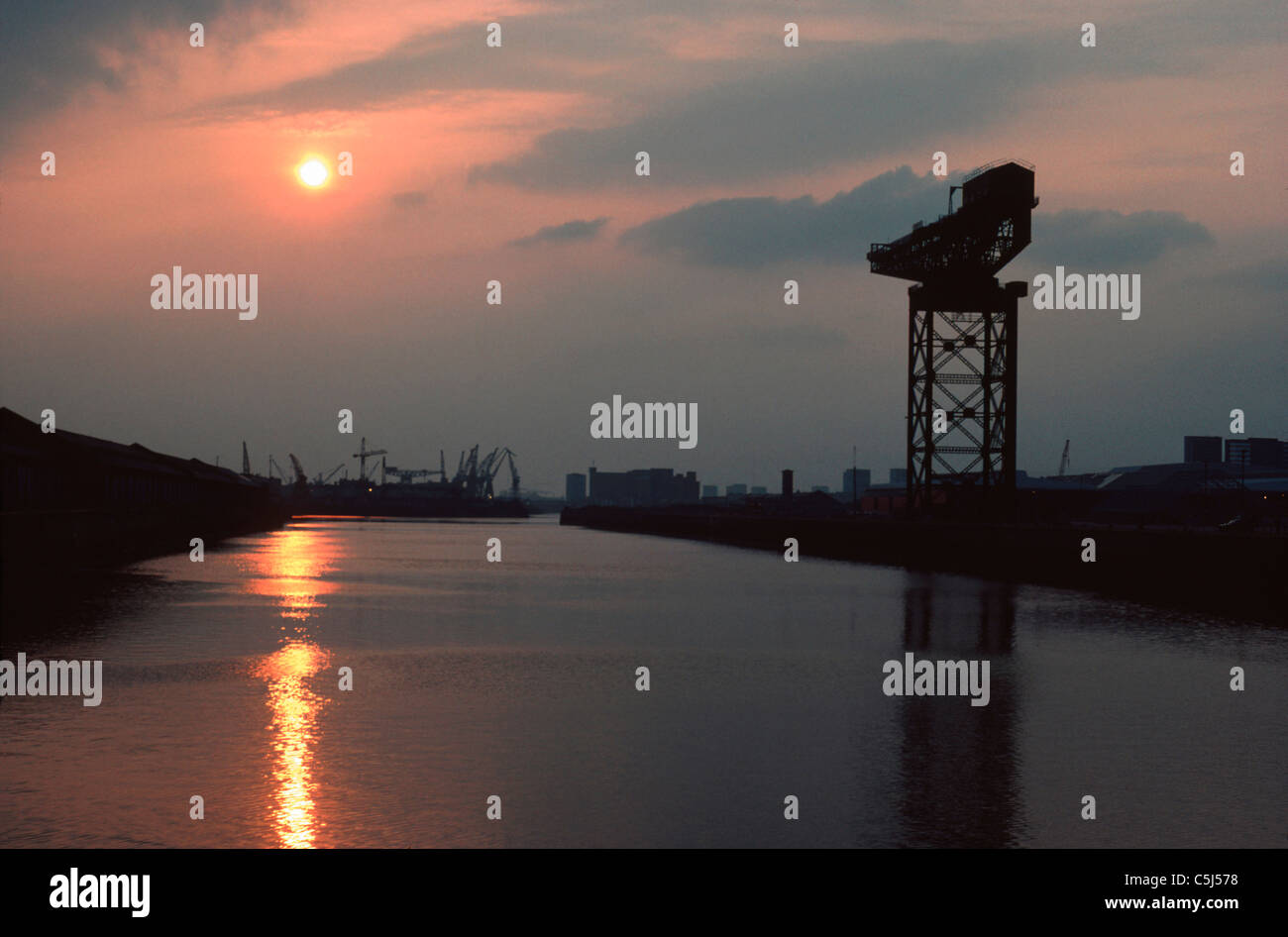 Historic block-setting crane beside the River Clyde, Glasgow, in sunset ...