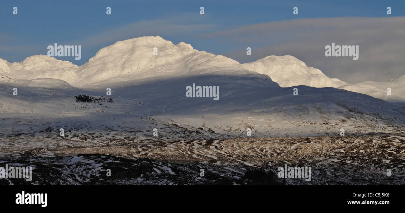 The snow-covered Tarmachan Hills in dappled light under a blue winter ...