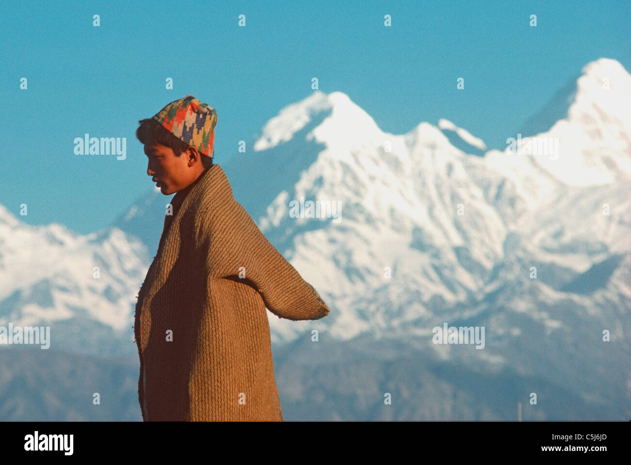 A native villager wears a cloak of woven straw against early-morning ...
