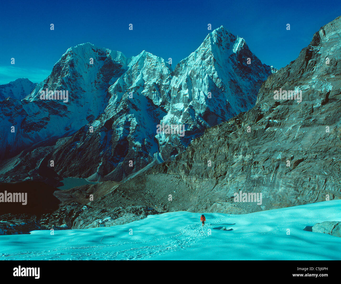 A lone climber comes up the lower slopes of Lobuche Peak with Cholatse ...